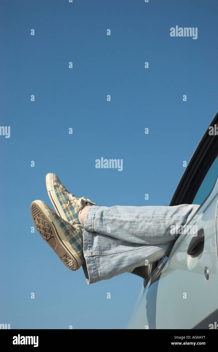 Young womans legs sticking out of car window Stock Photo - Alamy