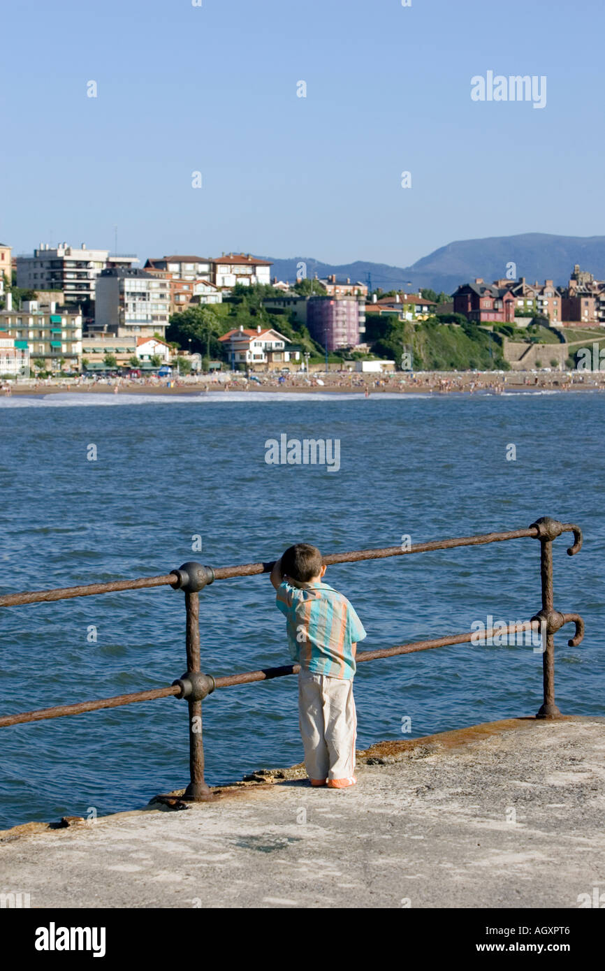 Small boy standing alone leaning against railing looking at sea Puerto ...