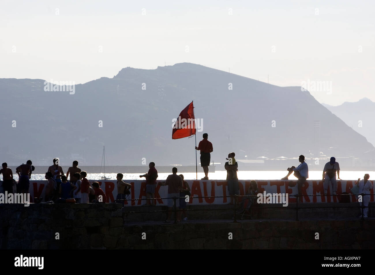 Man in silhouette holding red flag on sea wall during regatta Puerto ...