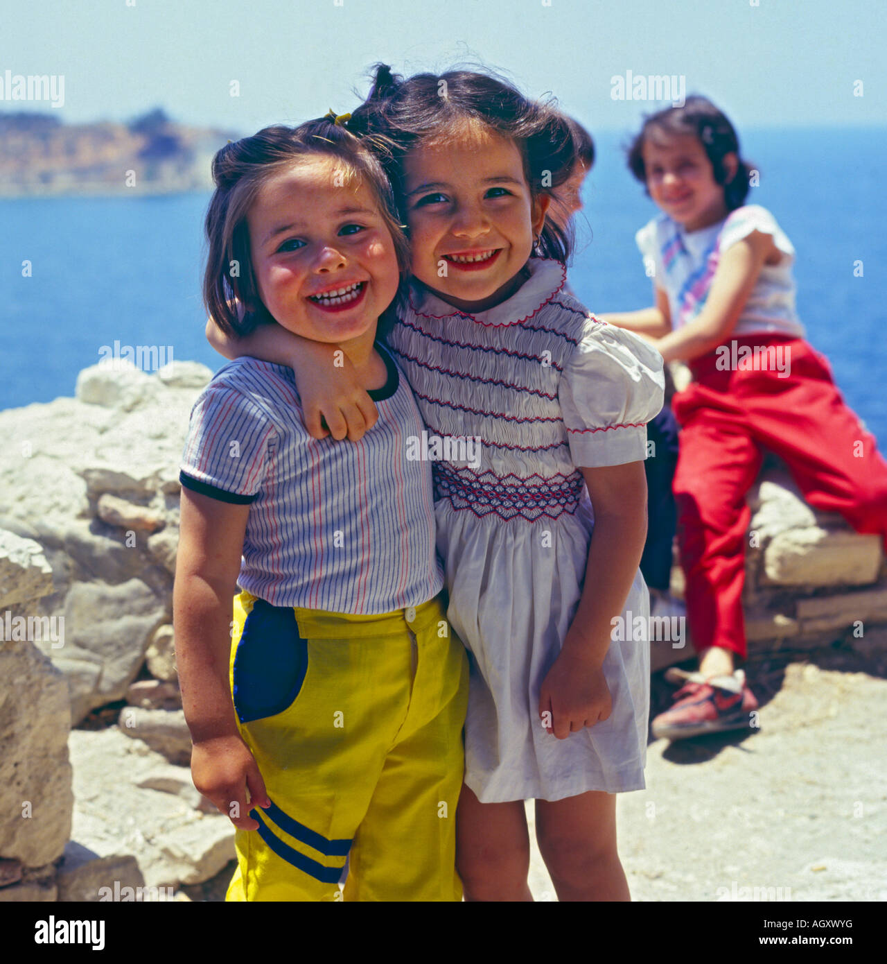 Two lovely little girls one with their arm around the other in a hug ...