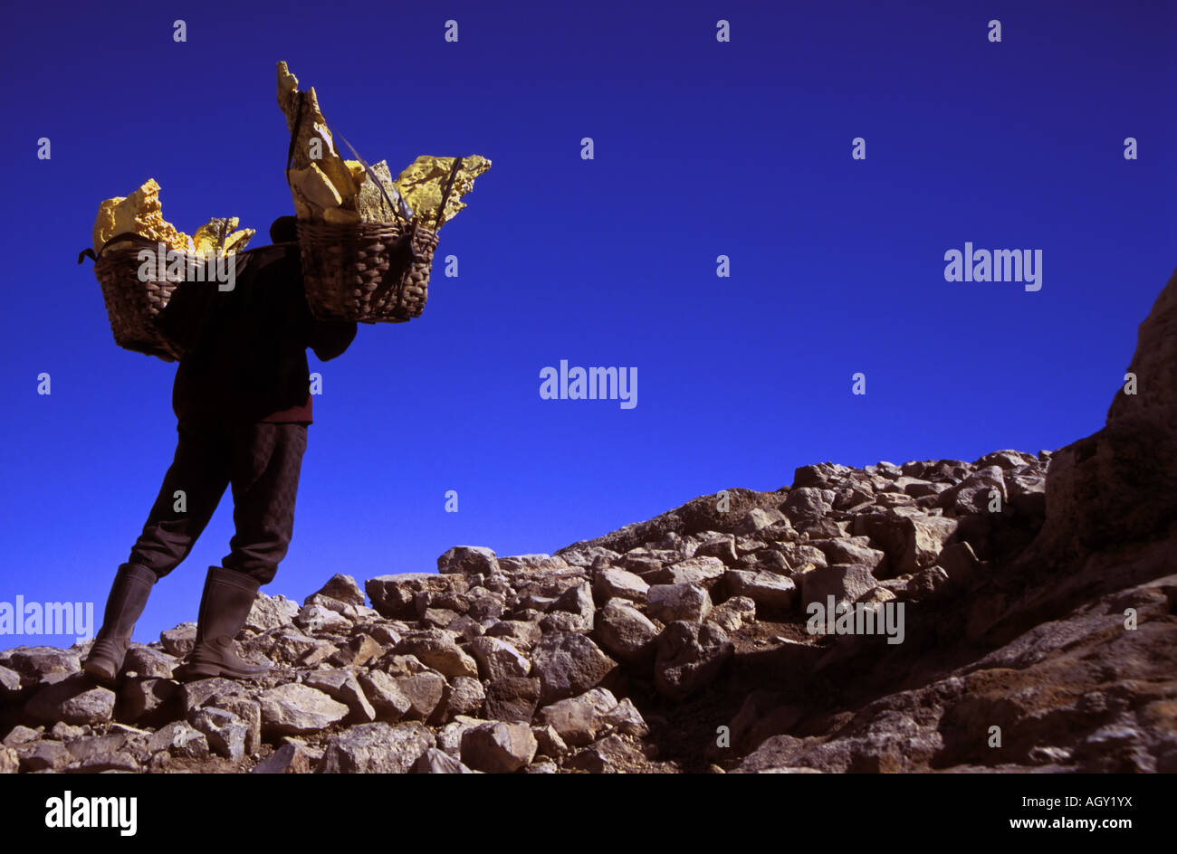 Miner climbing out of active volcanic crater carrying 90kg of yellow ...