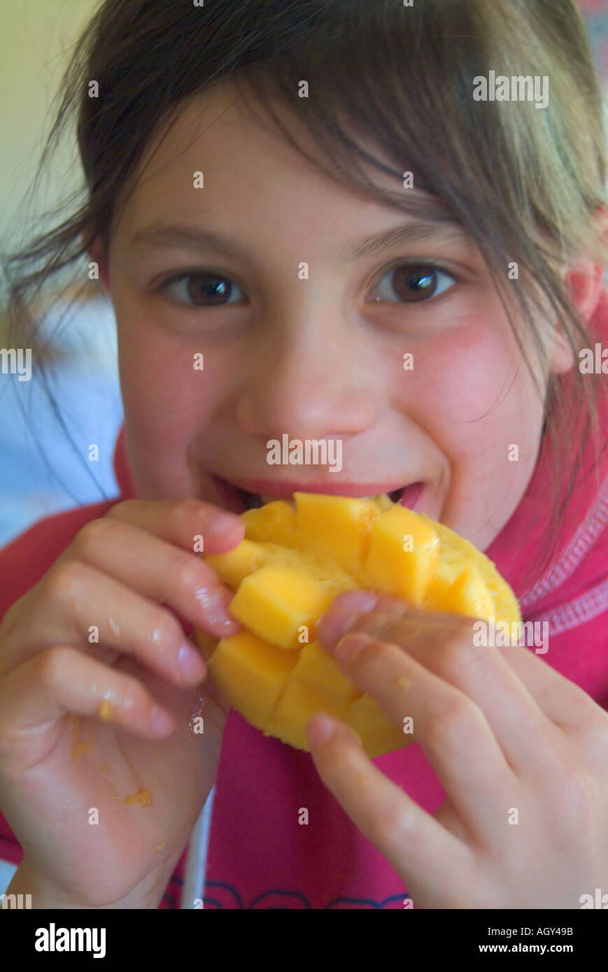 A young girl enjoying a sweet fresh mango Stock Photo - Alamy