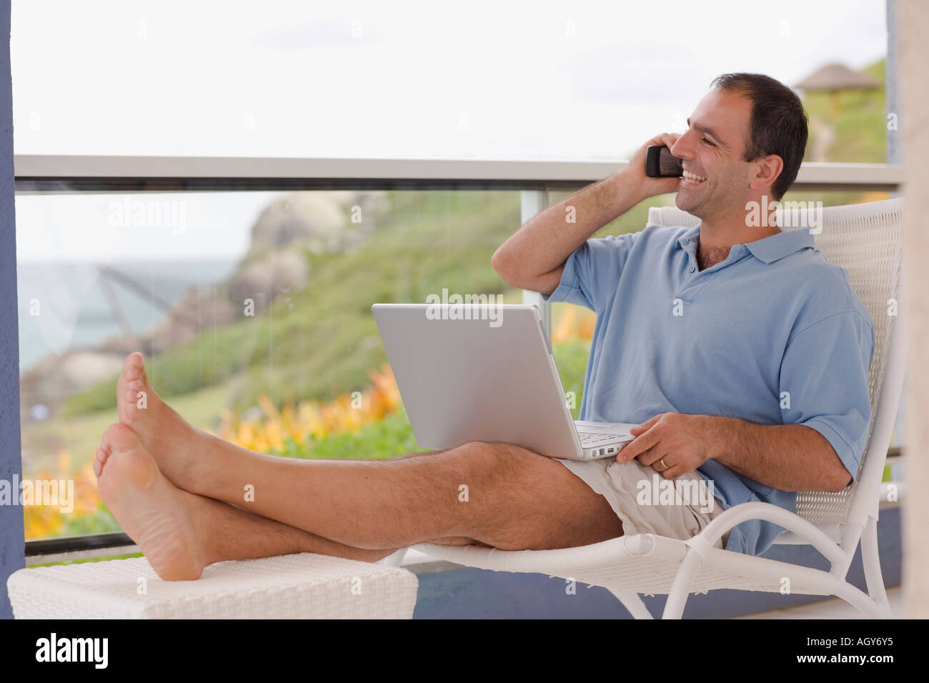 Man sitting on balcony with cell phone and laptop Florianopolis Brazil ...