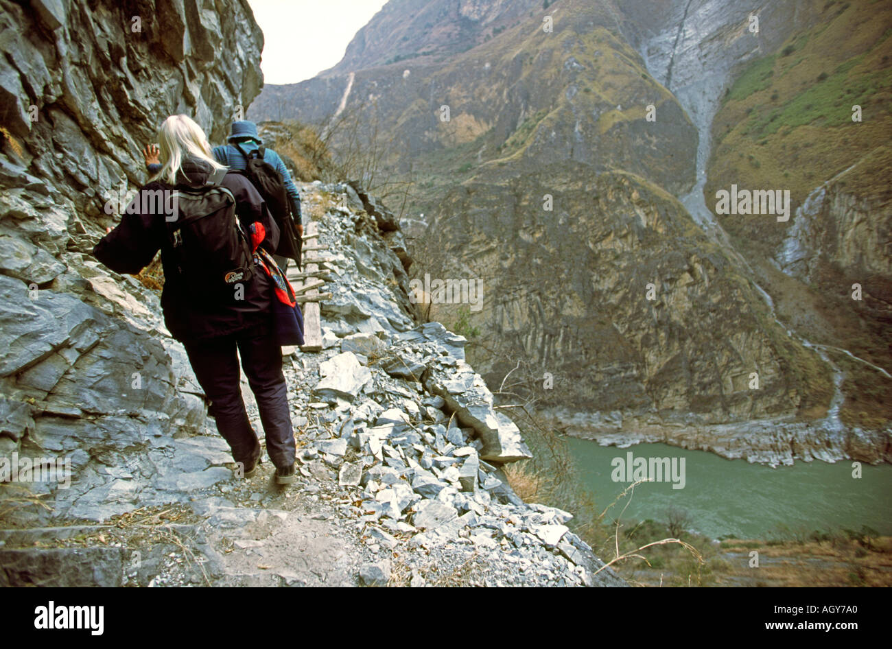 China Yunnan Tiger Leaping Gorge two tourists walking narrow path on ...