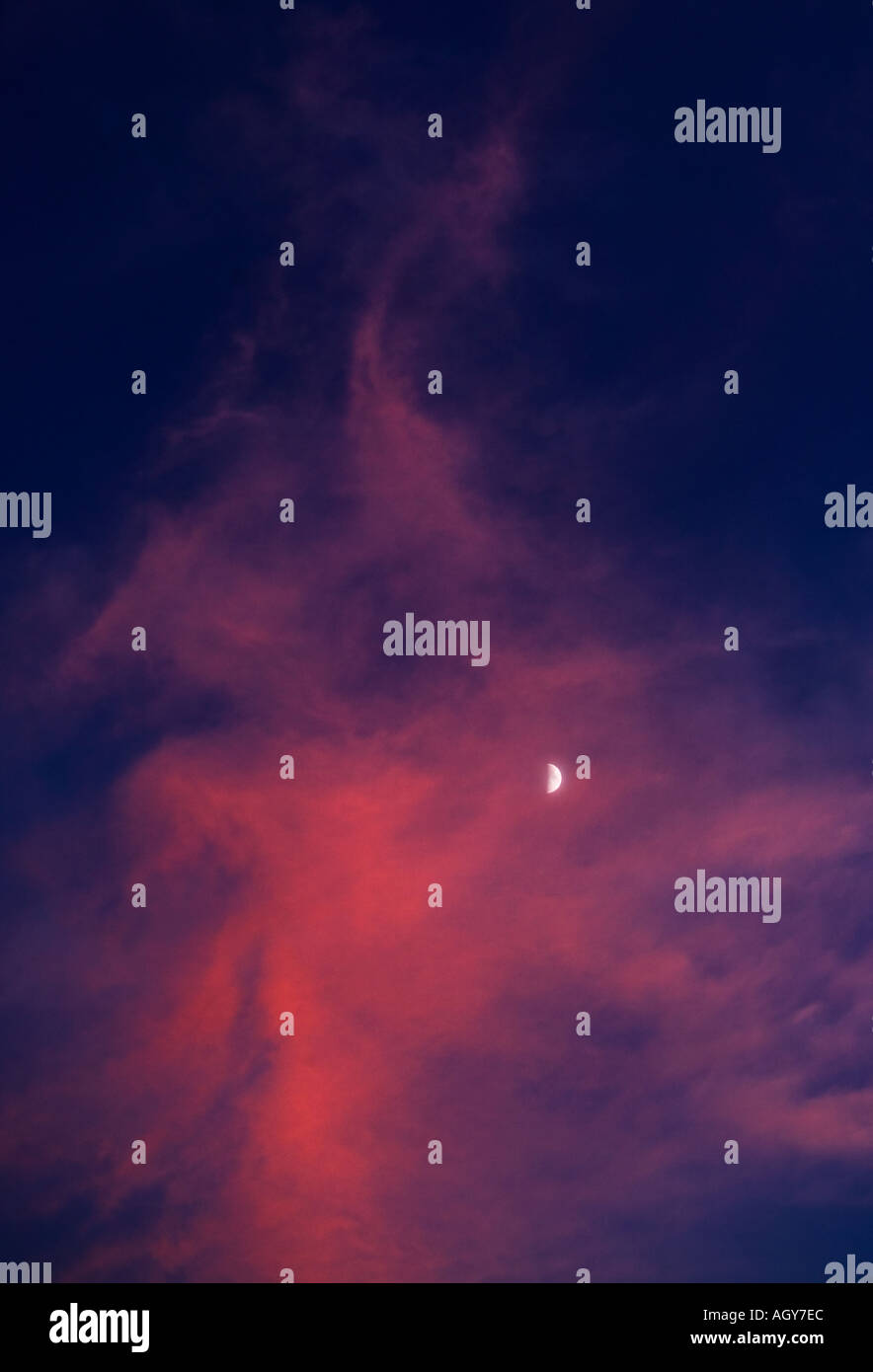 Moon peaks through sunset clouds during twilight hours Stock Photo - Alamy
