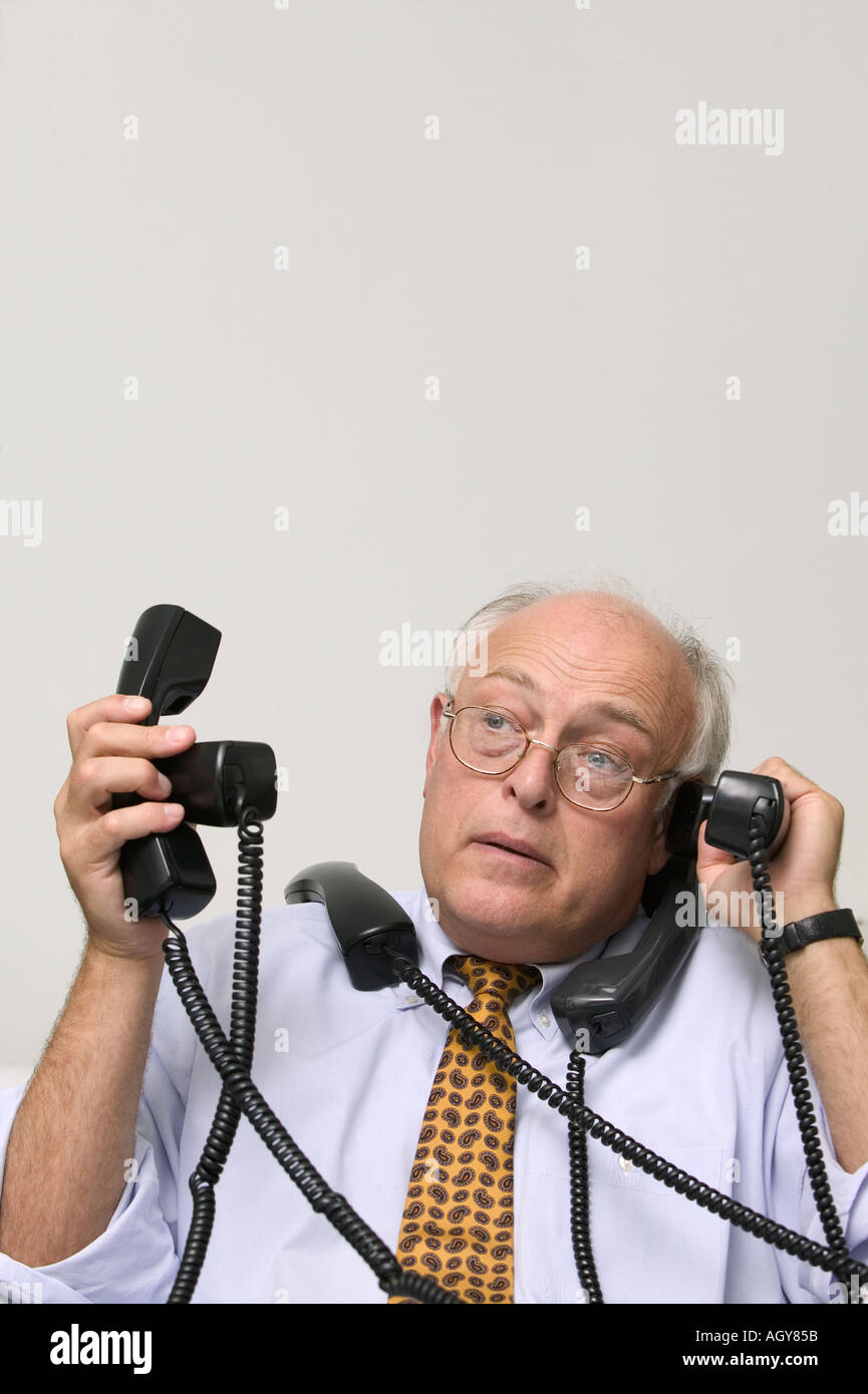 Aging executive on several phones at once in office building Stock ...