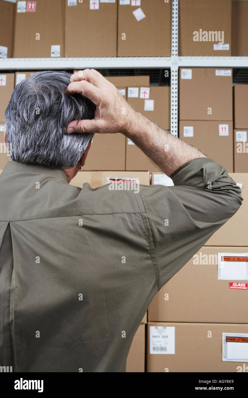 Businessman in warehouse scratching his head Stock Photo - Alamy