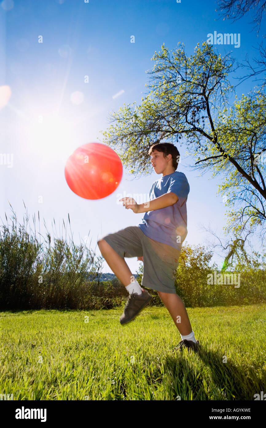 Boy kicking ball in bright sunlight Stock Photo - Alamy