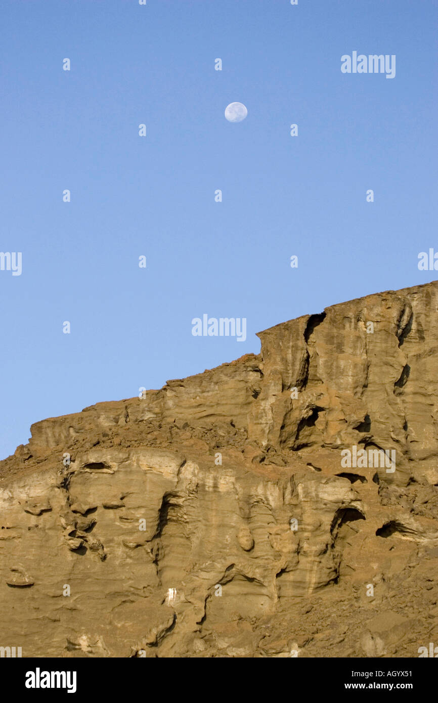 the moon showing above weathered volcanic tuff rock Galapagos islands ...