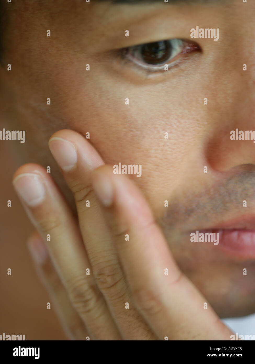 Close up of a mid adult man with his hand on his cheek Stock Photo - Alamy
