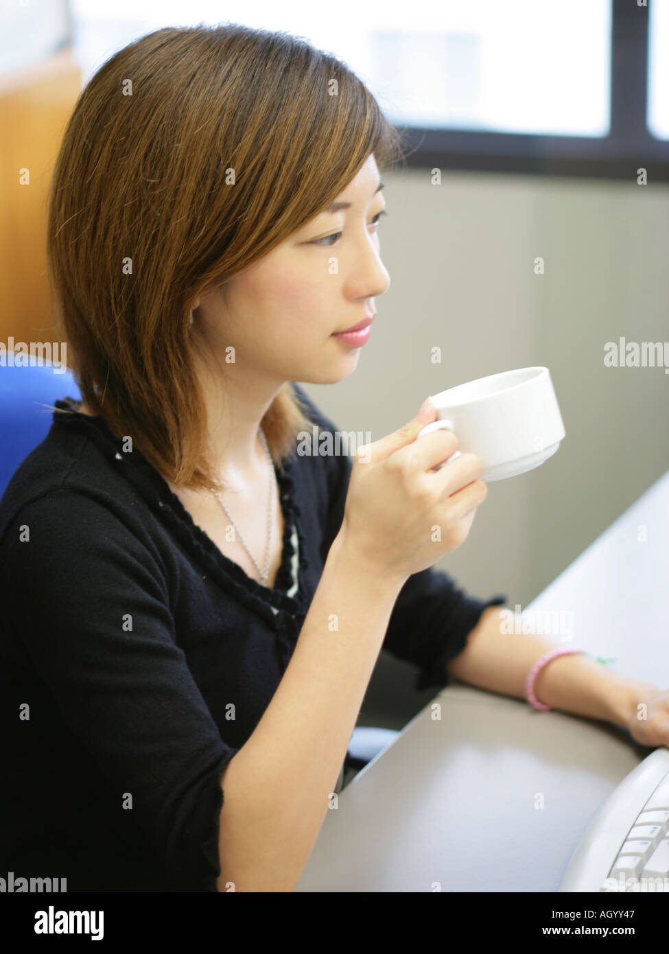 Side profile of a businesswoman drinking coffee at her desk Stock Photo ...