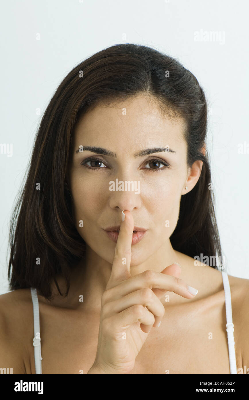 Woman holding finger over lips, looking at camera, portrait Stock Photo ...