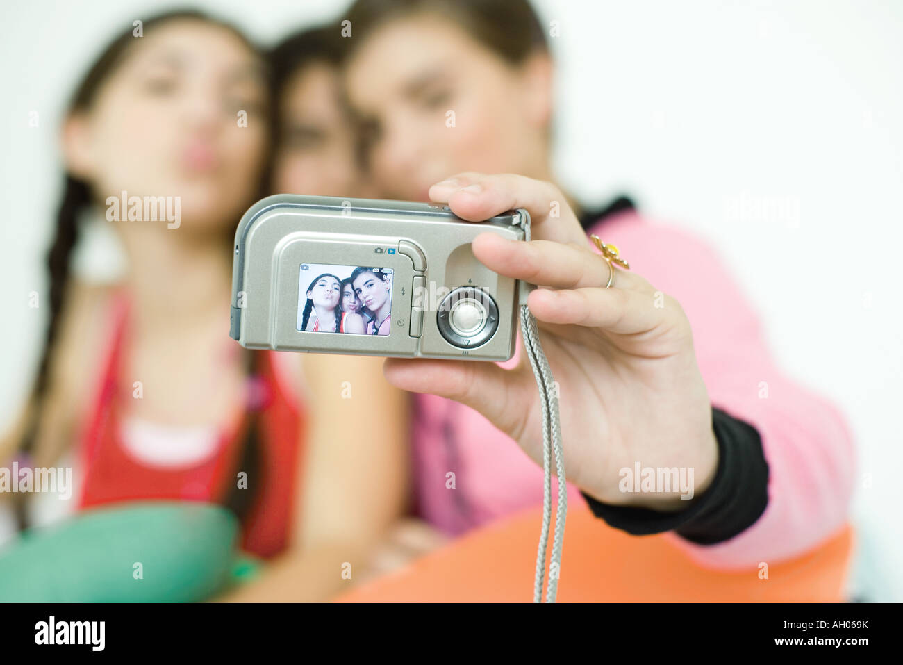 Three young female friends taking photo of selves with digital camera ...