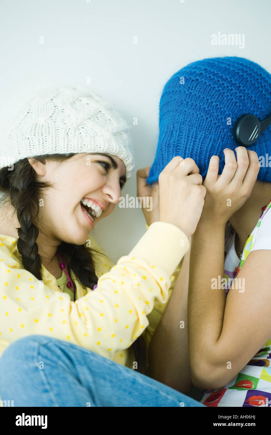 Two young female friends, one hiding face under hat Stock Photo - Alamy
