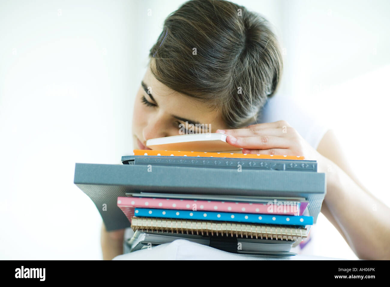 Teen girl resting head on stack of homework, eyes closed Stock Photo ...