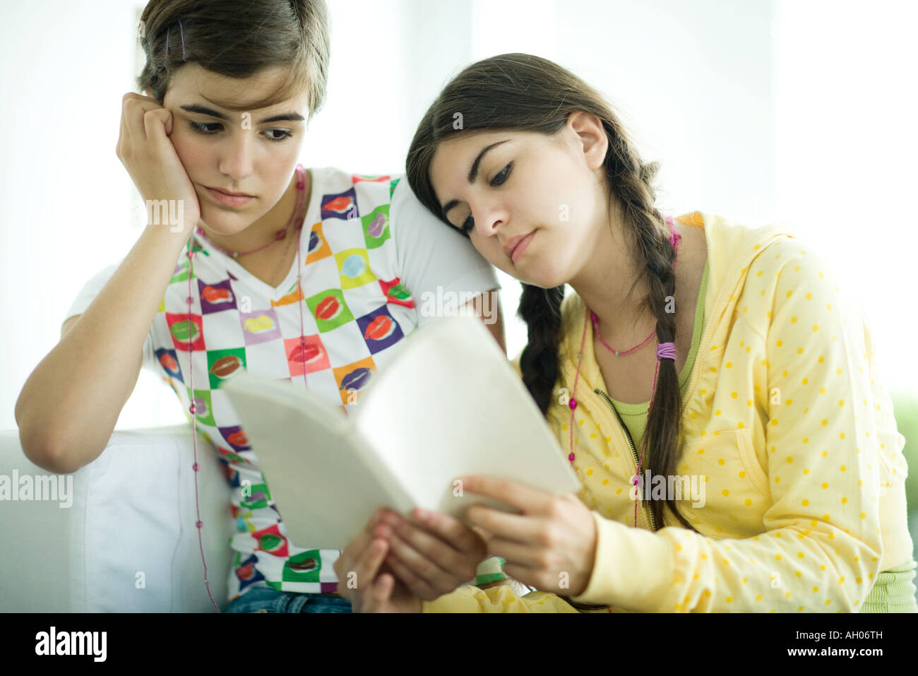Young female friends reading book together Stock Photo - Alamy