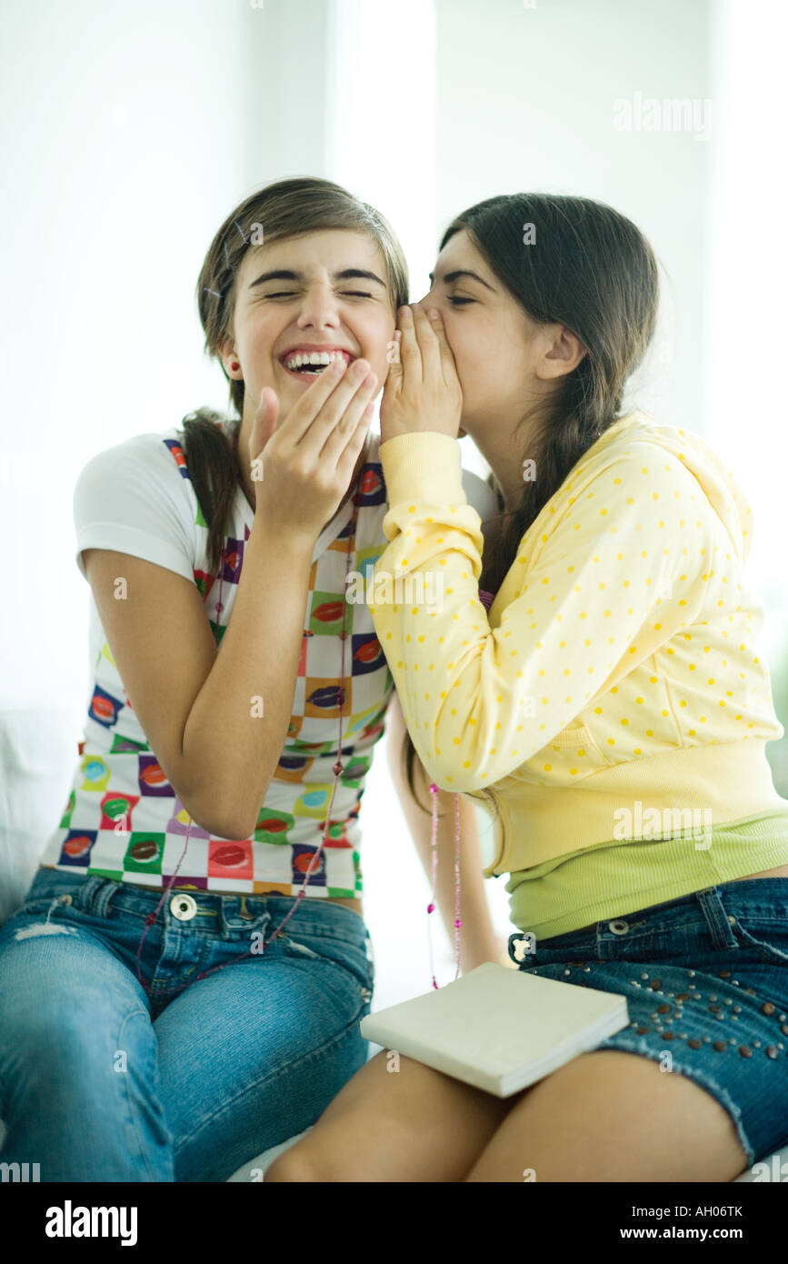 Young female friends, one whispering while the other laughs Stock Photo ...