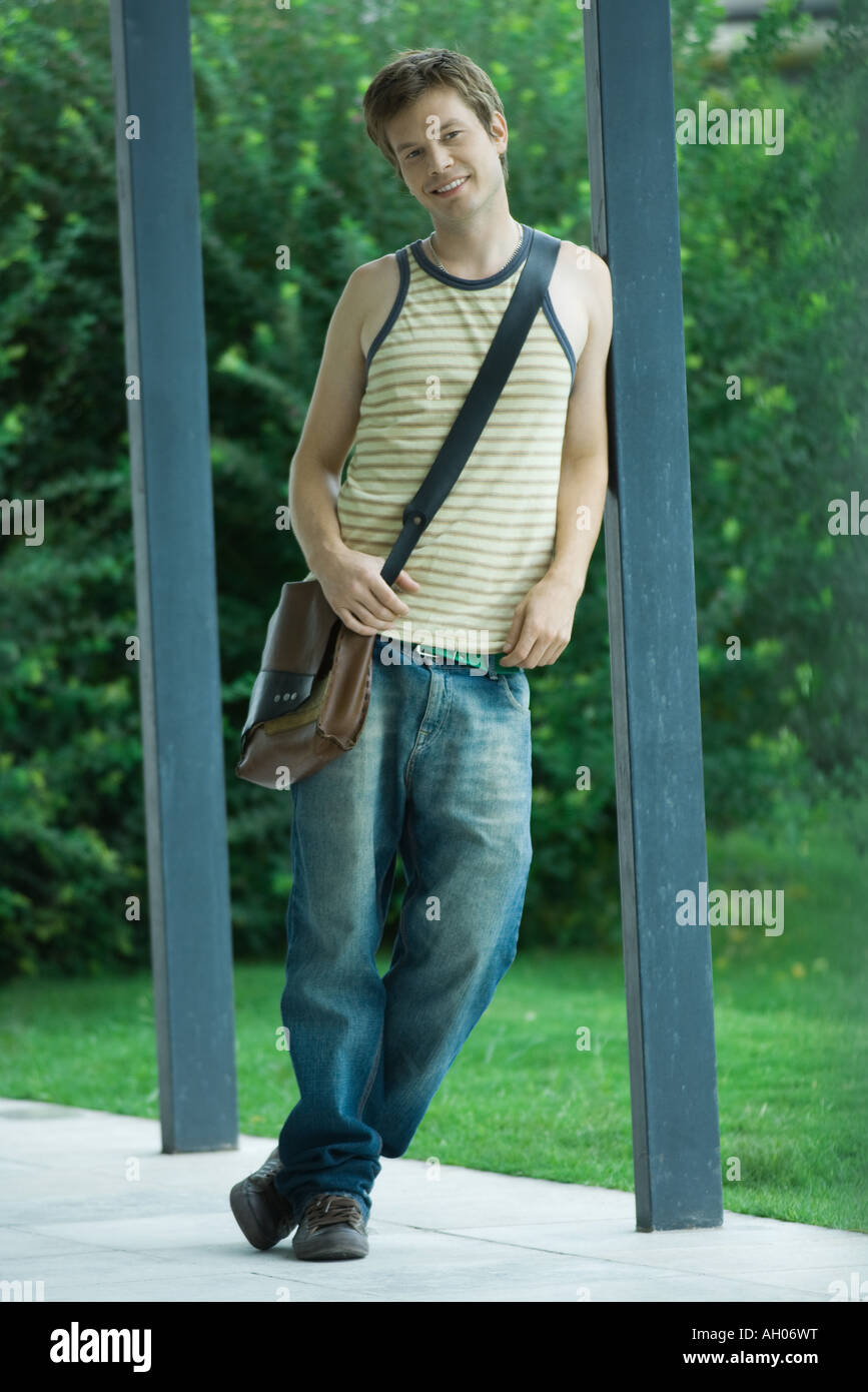 Man standing leaning against post, smiling, full length portrait Stock ...