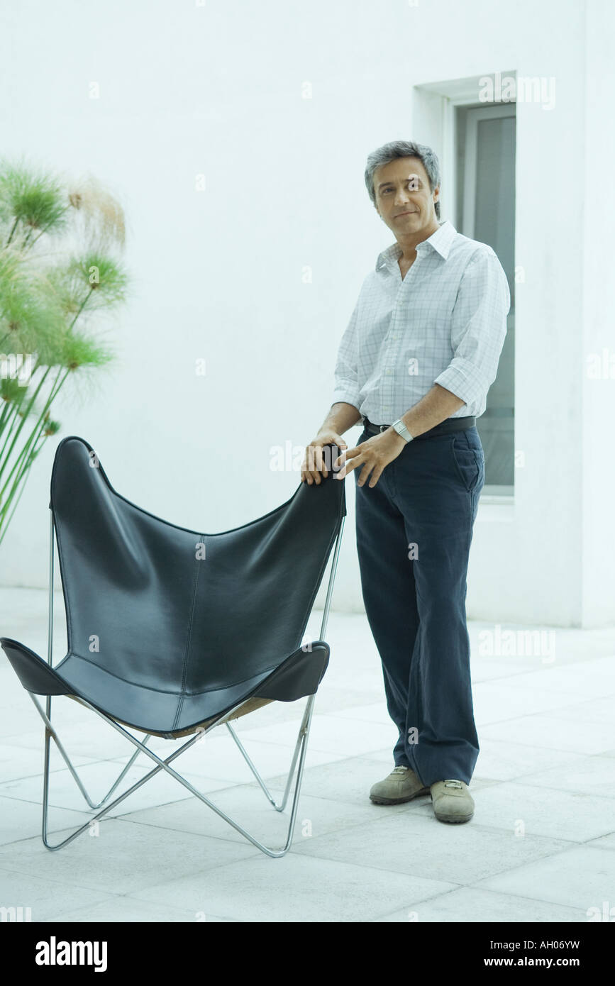 Mature man standing by chair, full length portrait Stock Photo - Alamy