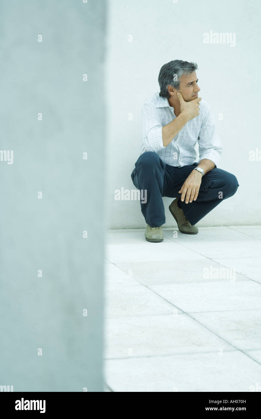 Mature man crouching, looking away, full length portrait Stock Photo ...