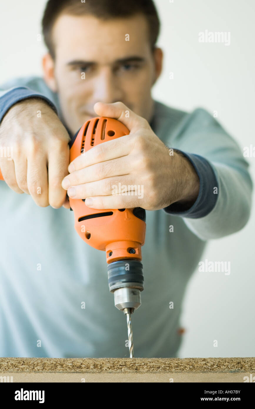Man using drill, focus on drill in foreground Stock Photo - Alamy
