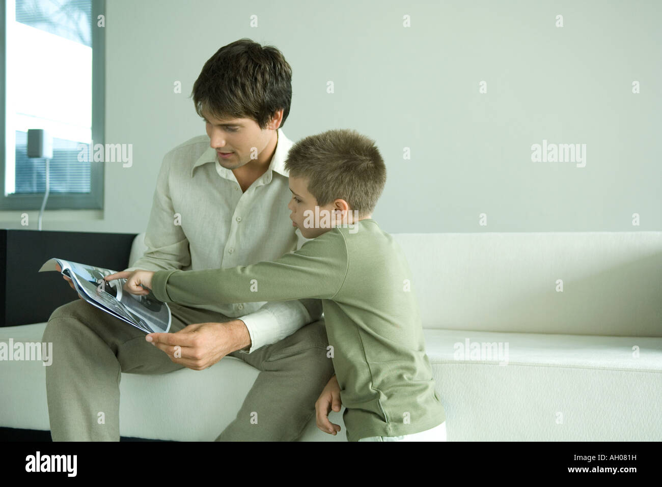 Boy and father looking at magazine together Stock Photo - Alamy