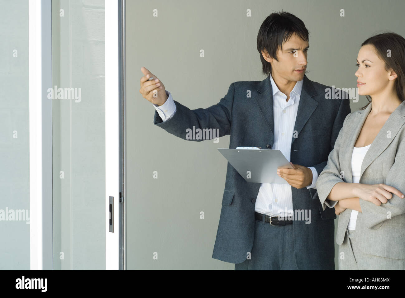 Male real estate agent showing house to female client, standing by ...
