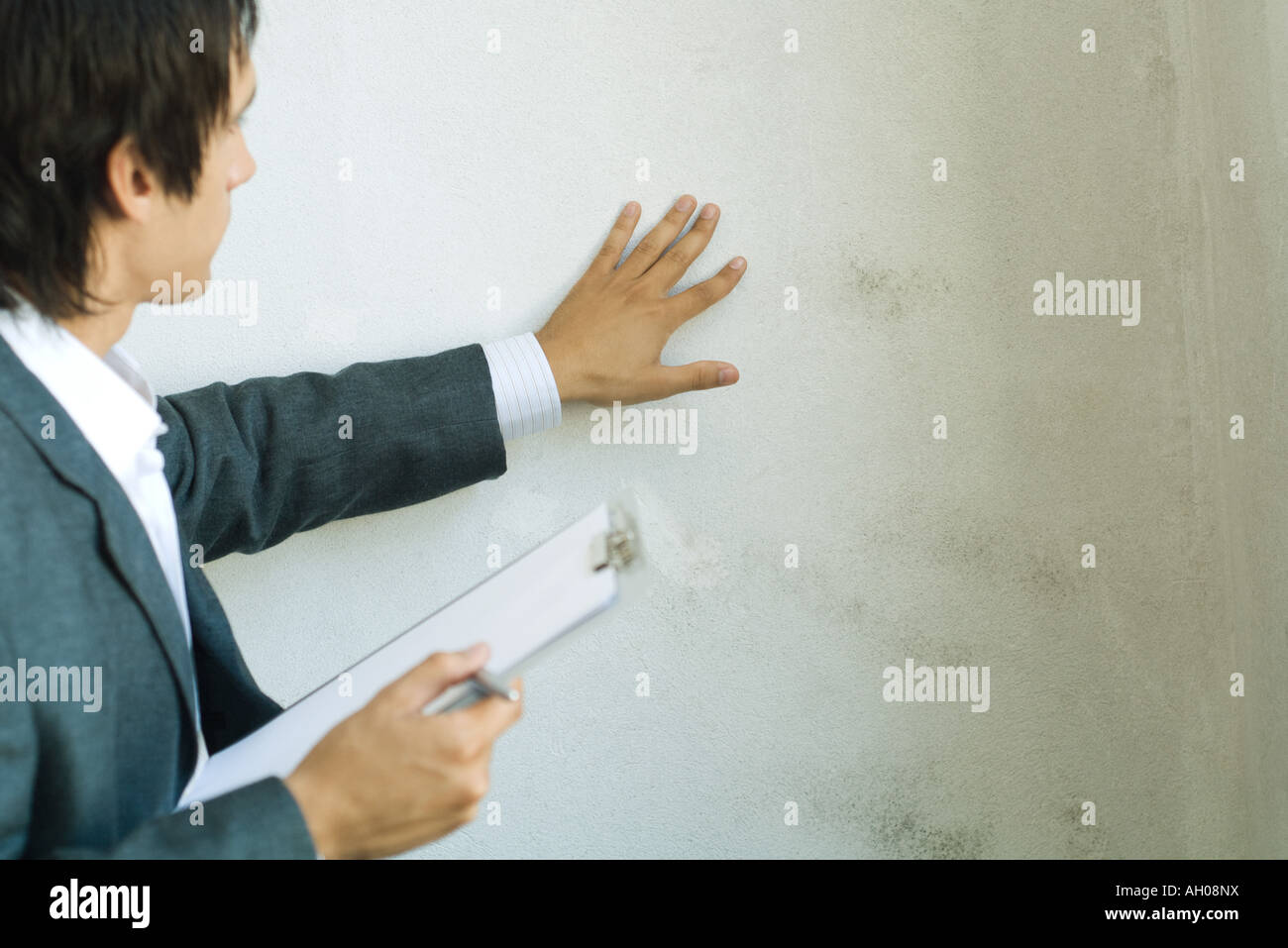 Man in suit holding clipboard, touching wall Stock Photo - Alamy
