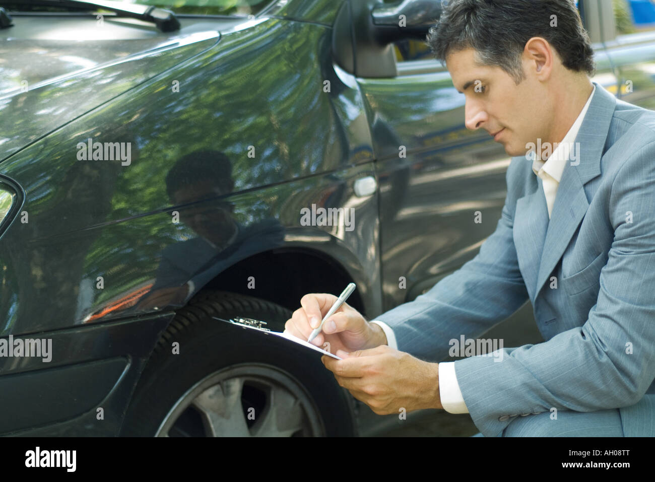 Mature man in suit inspecting car Stock Photo - Alamy