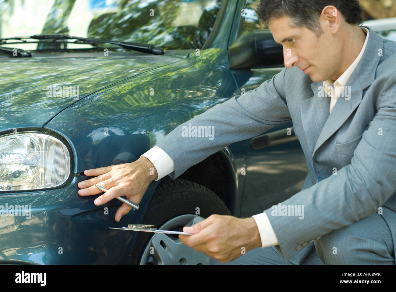 Mature man in suit inspecting car Stock Photo - Alamy