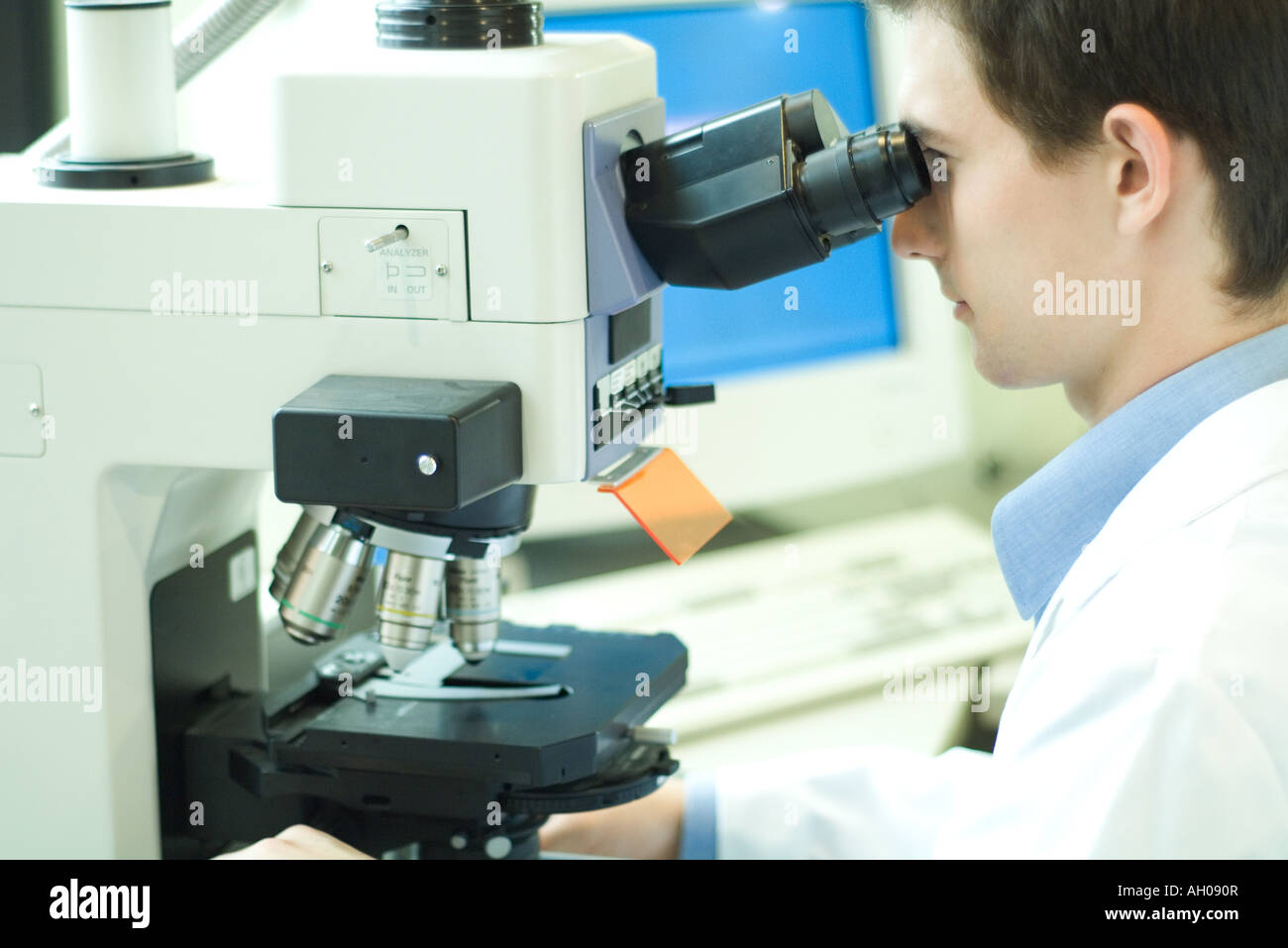 Young male scientist looking through microscope Stock Photo - Alamy