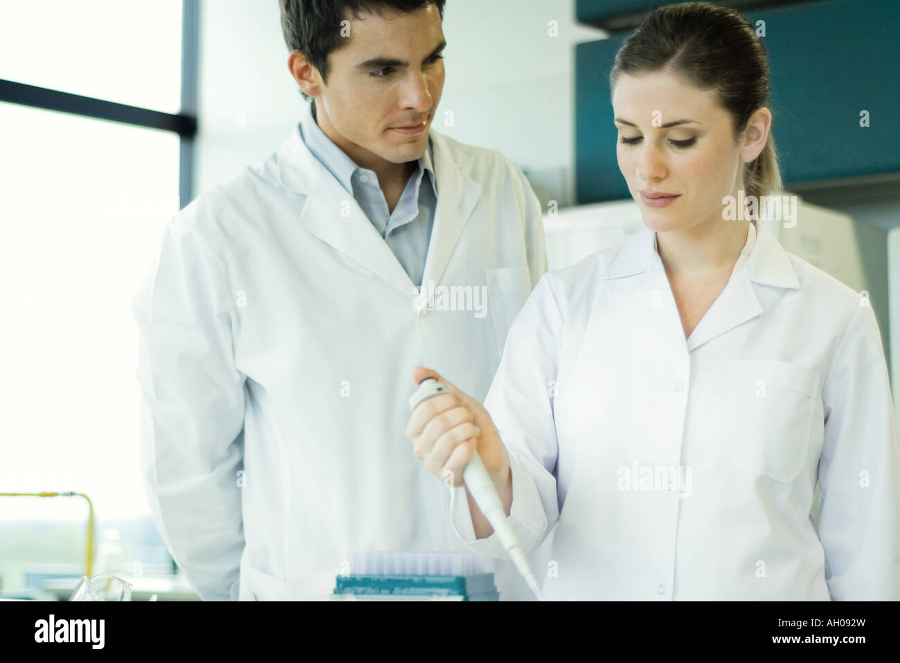 Female lab worker holding dropper, male colleague watching her Stock ...