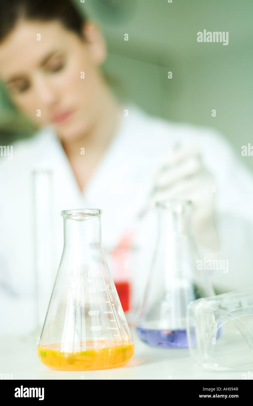 Female scientist working in laboratory, focus on lab glassware in ...