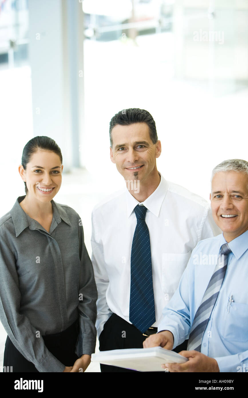 Three business associates standing together, smiling at camera Stock ...