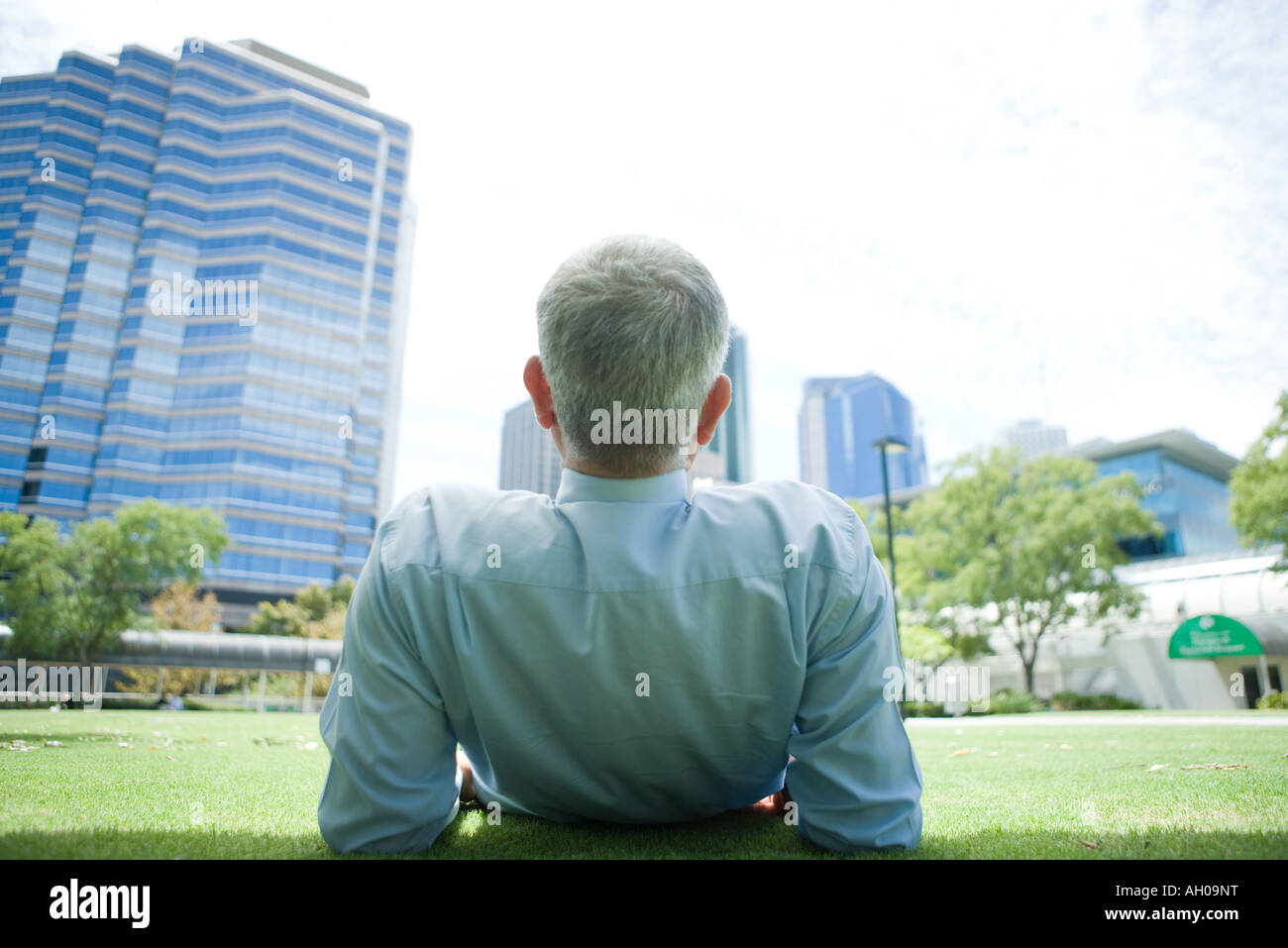 Mature man reclining on ground, looking at urban scene, rear view Stock ...