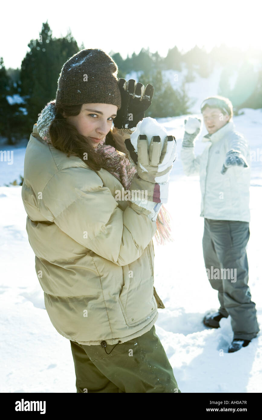 Two young friends holding up snowballs, one looking over shoulder at ...