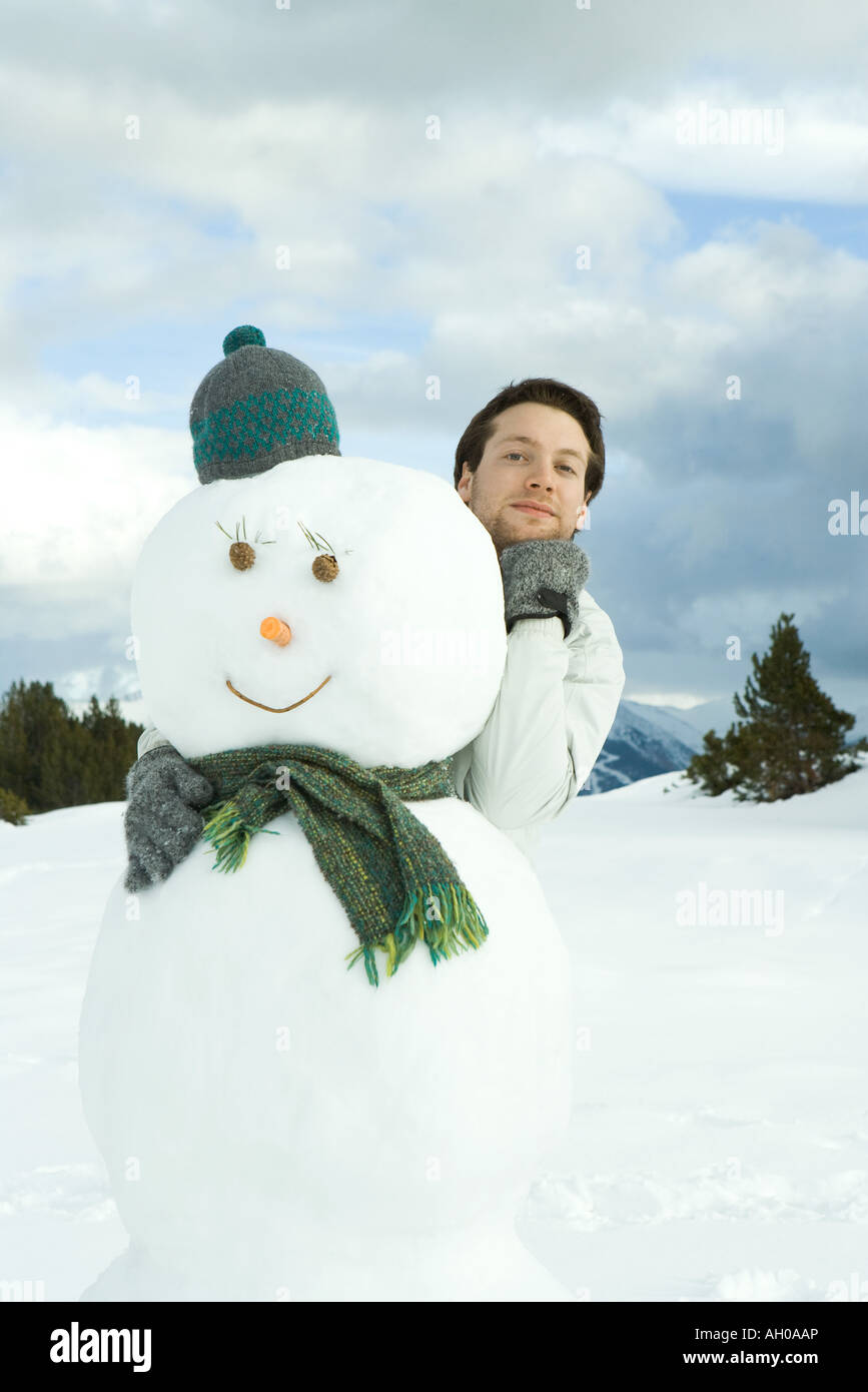 Young man embracing snowman, hand under chin, portrait Stock Photo - Alamy