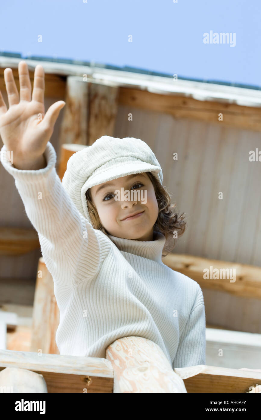 Girl waving to camera from deck of chalet, low angle view Stock Photo ...