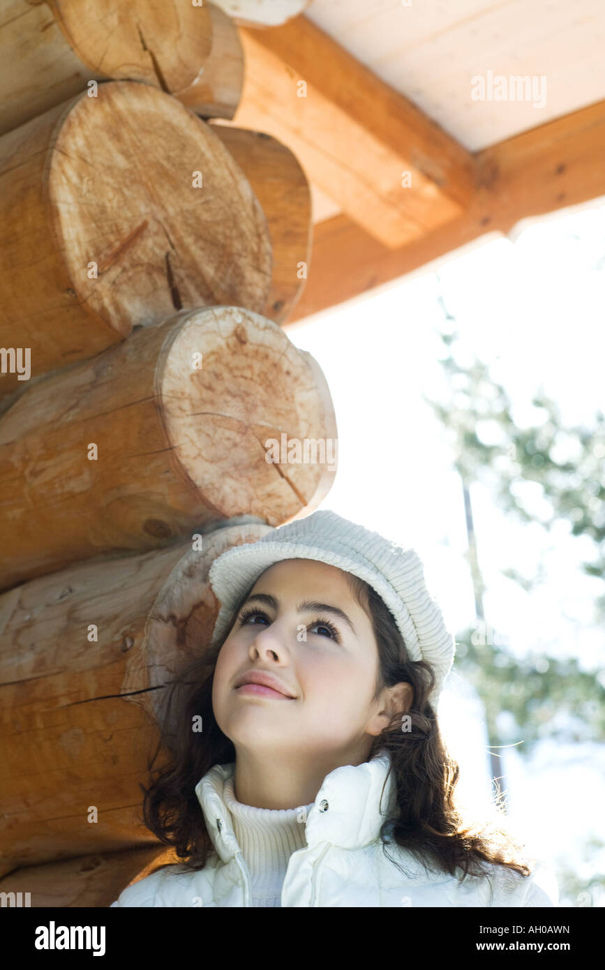 Teenage girl looking up, standing next to log cabin, portrait Stock ...
