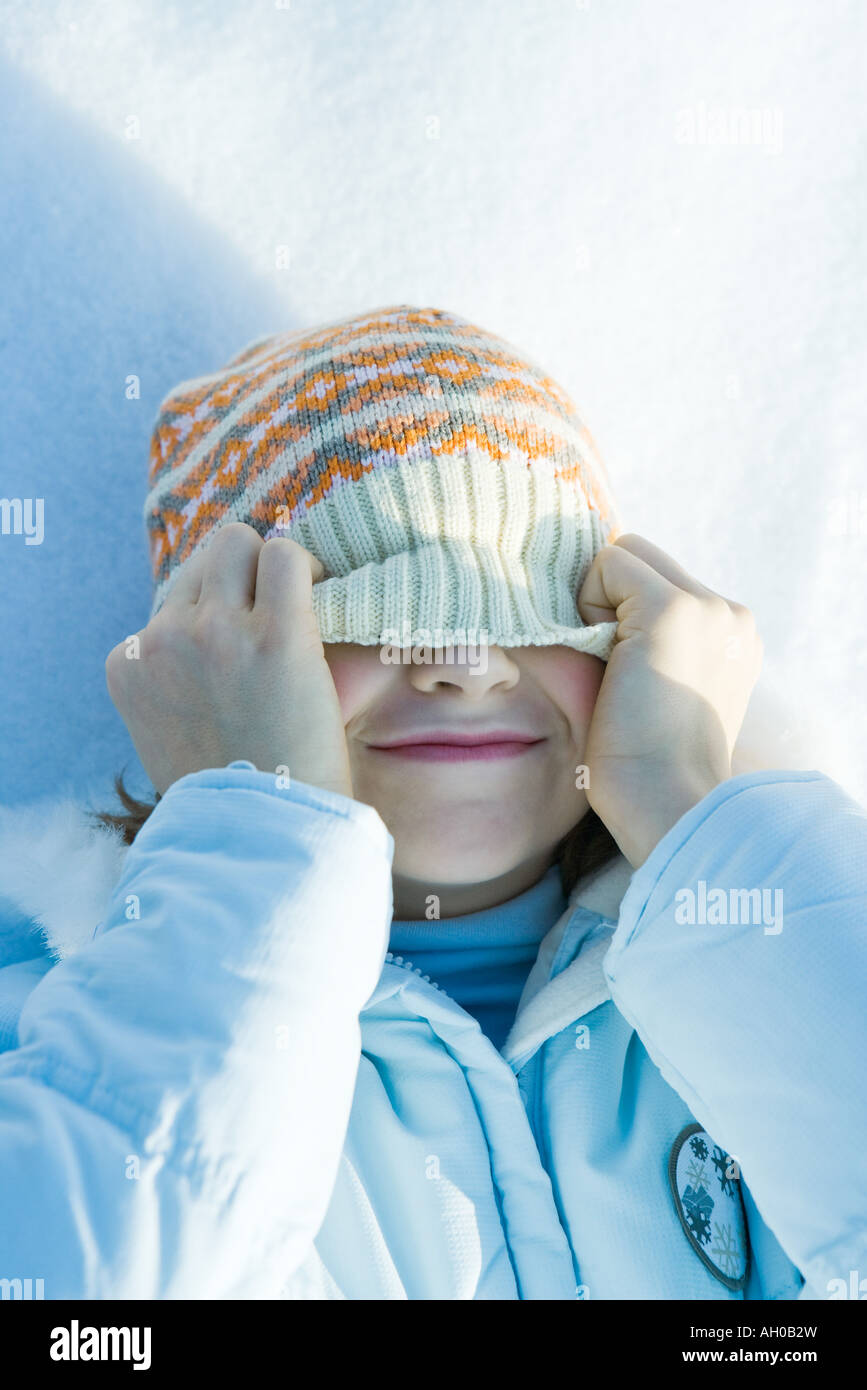 Girl lying on snow, pulling hat over eyes Stock Photo - Alamy
