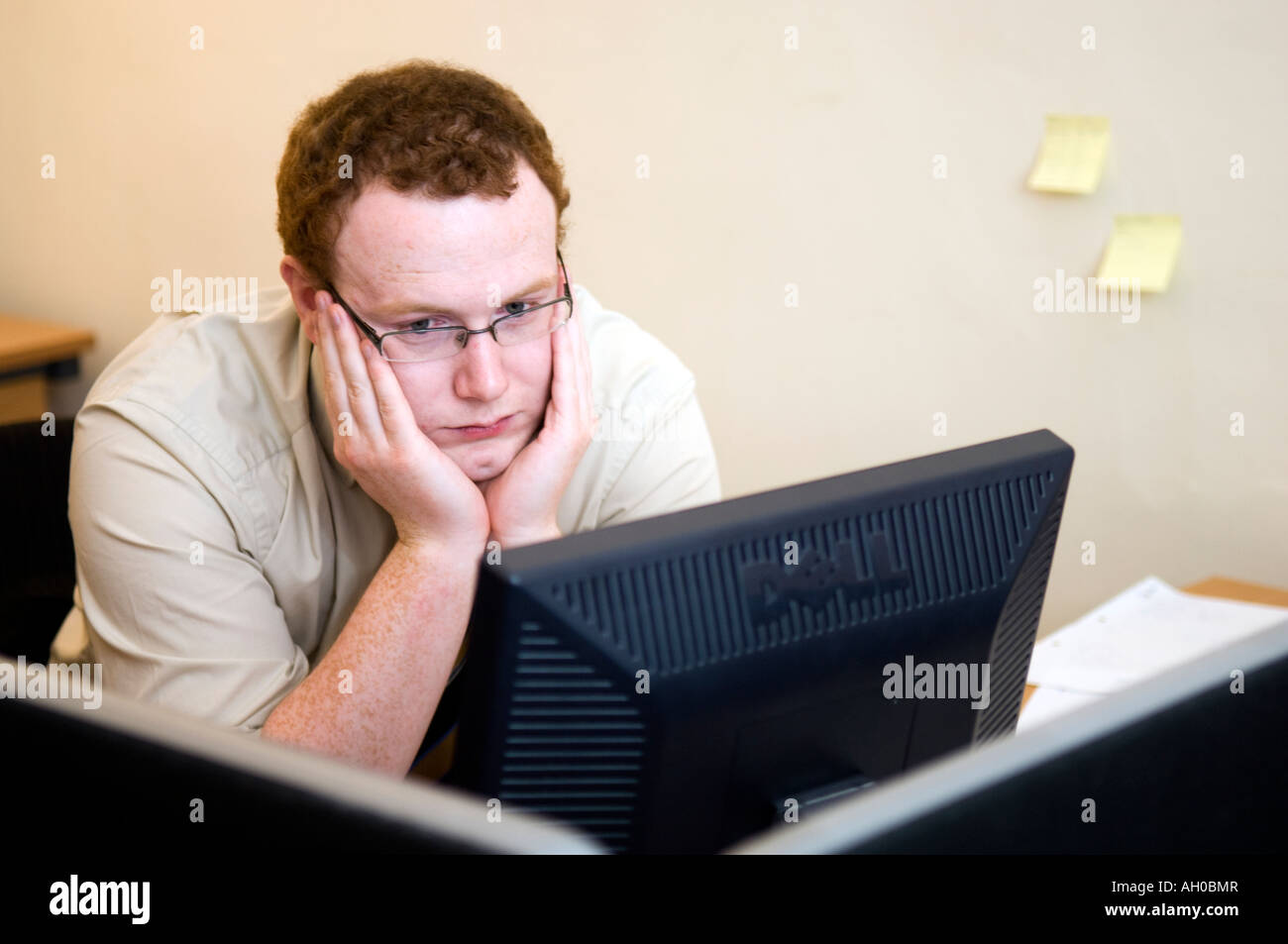 Male officer worker looking very bored whilst reading his computer ...