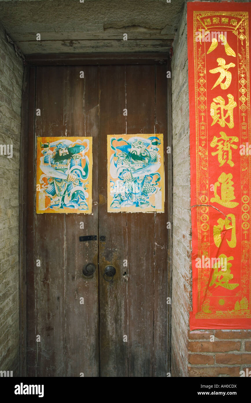 China, doorway with posters, banner with Chinese script next to door ...