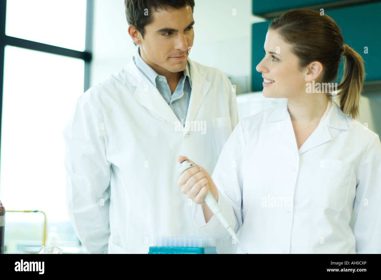 Young female lab worker smiling at supervisor Stock Photo - Alamy