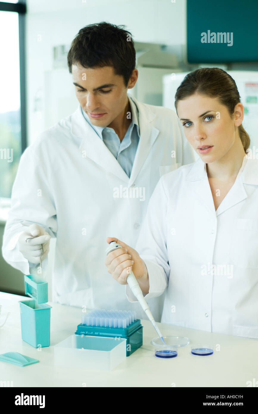 Male and female lab workers standing side by side, woman looking at ...