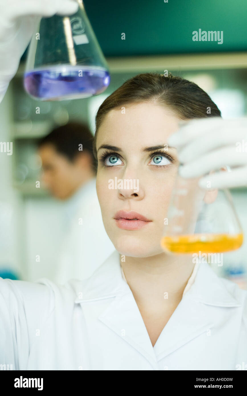 Young woman in research lab, holding up two flasks Stock Photo - Alamy