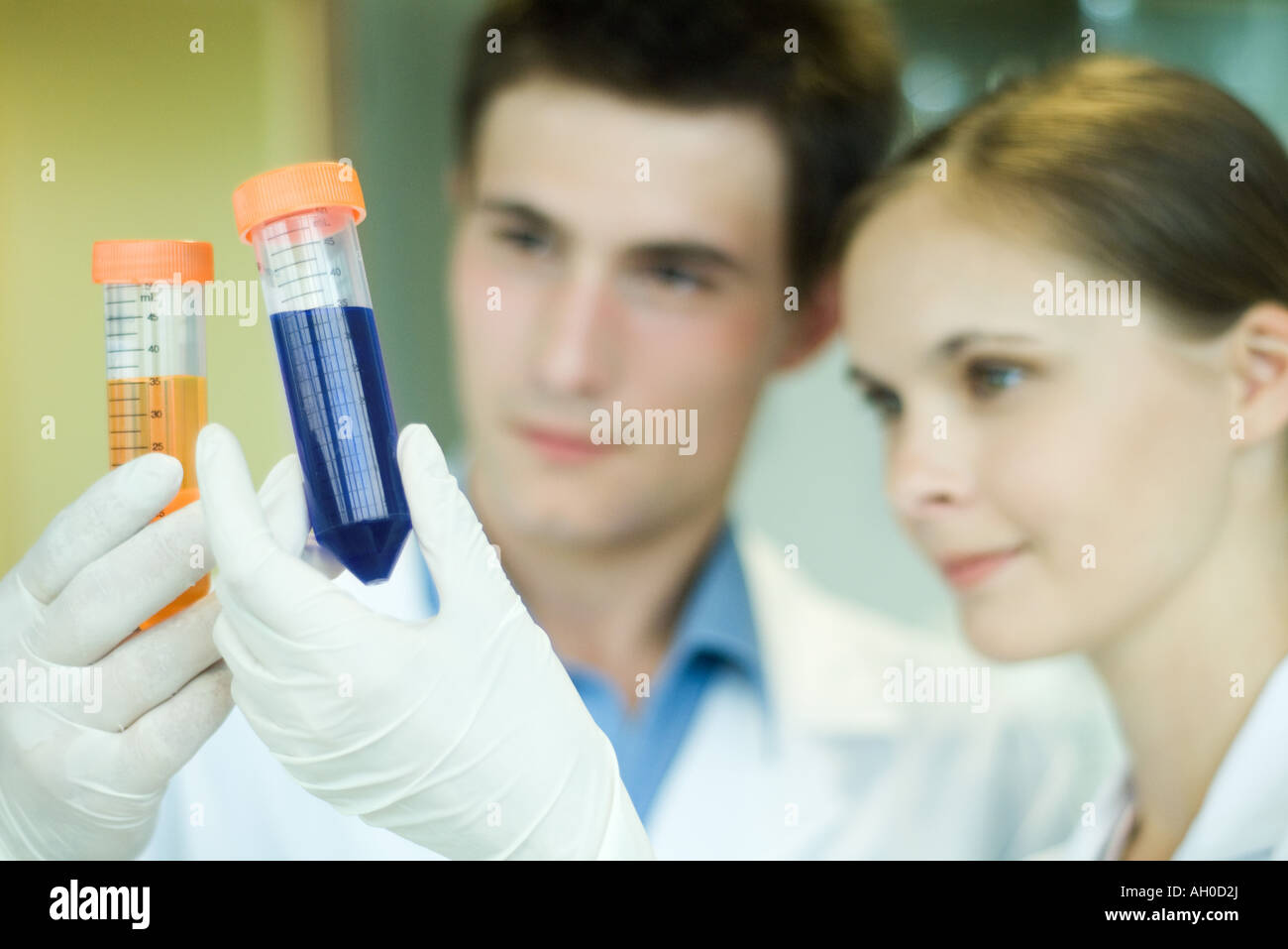 Young male and female lab workers, holding up test tubes Stock Photo ...