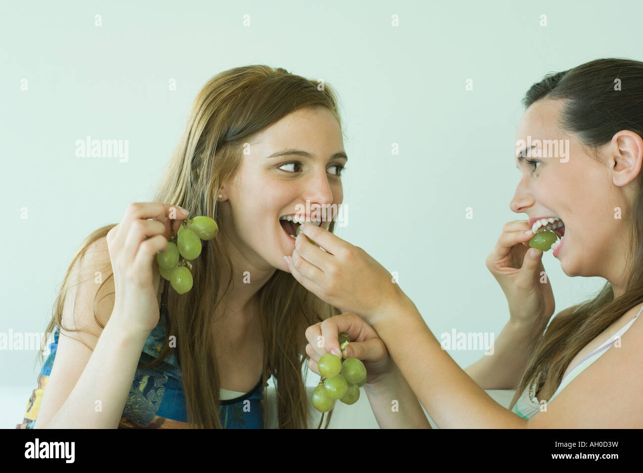 Two young friends feeding each other grapes, smiling Stock Photo - Alamy