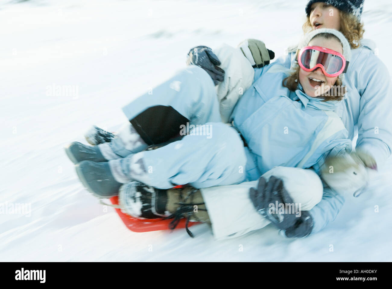 Two young friends riding sled together, blurred motion Stock Photo - Alamy