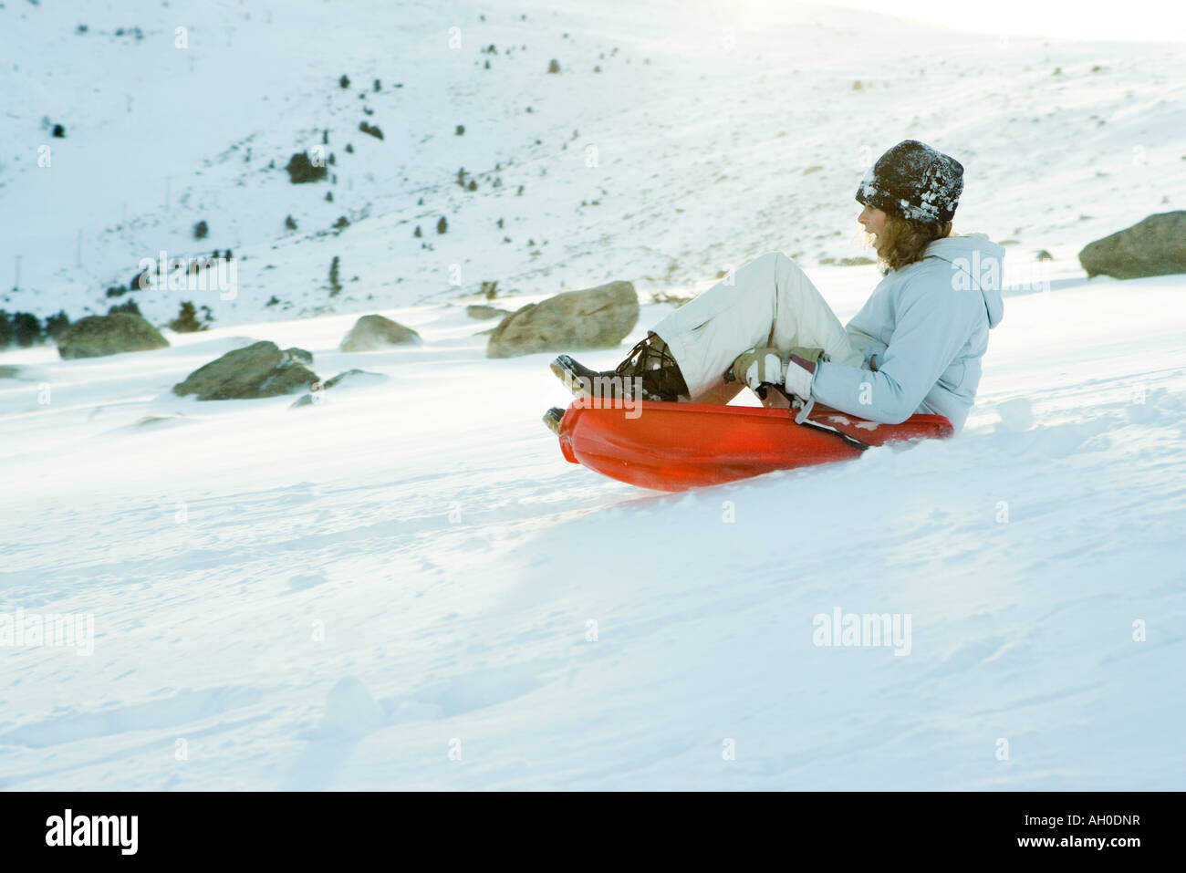Teenage girl riding sled on ski slope, side view, full length Stock ...