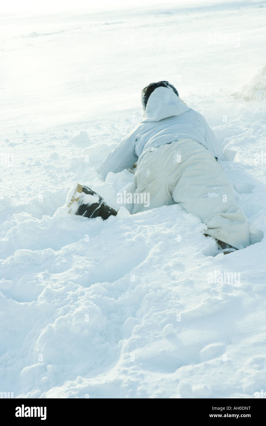 Young person lying on stomach in snow, fallen, rear view Stock Photo ...